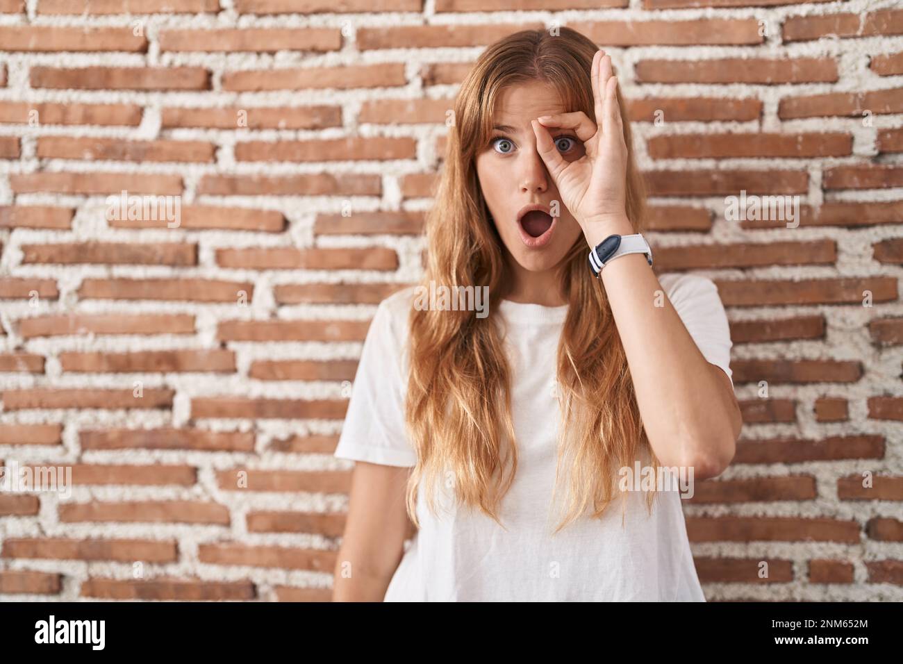Young caucasian woman standing over bricks wall doing ok gesture ...