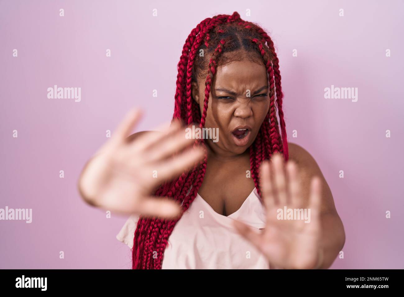 African american woman with braided hair standing over pink background ...