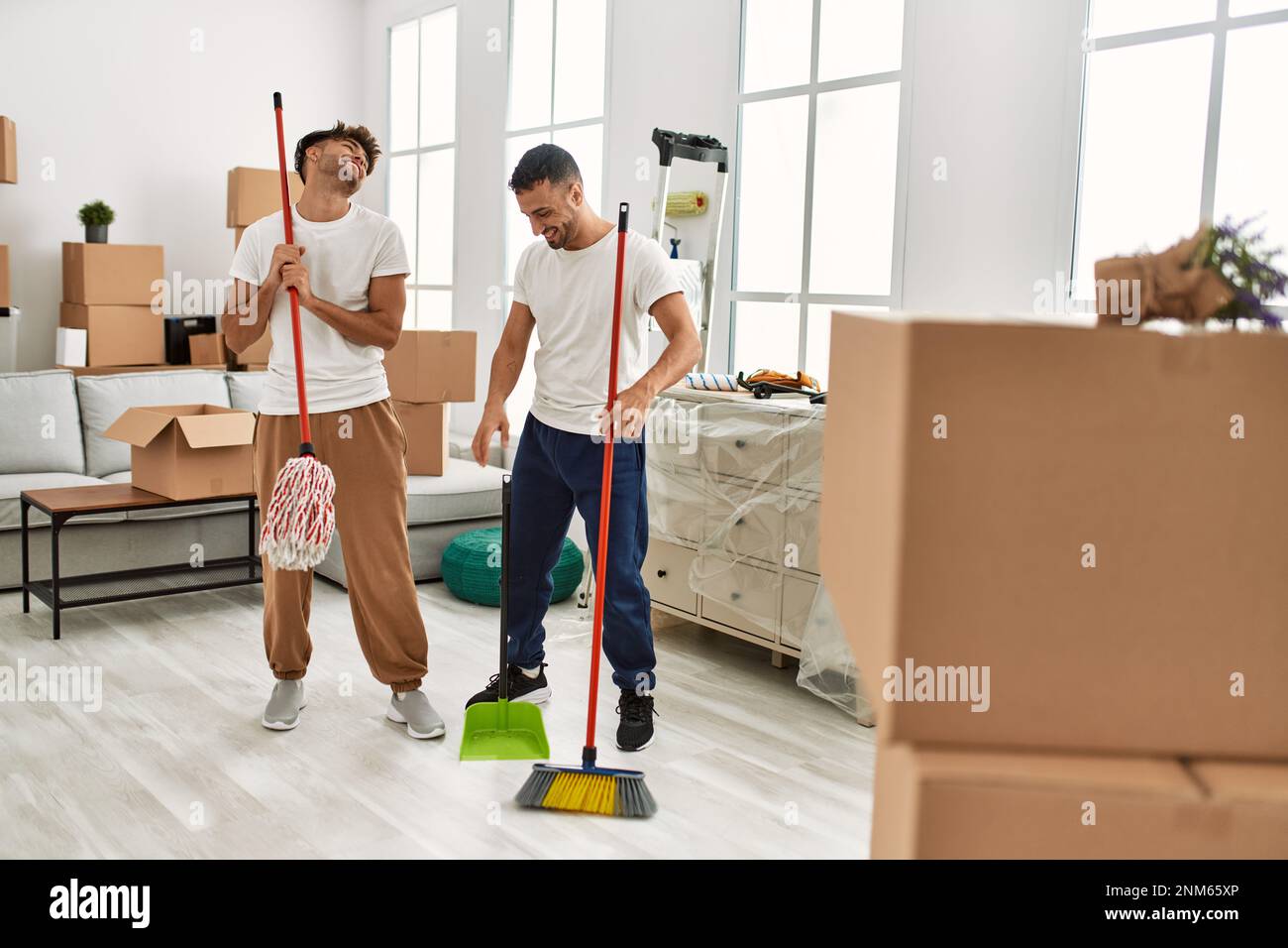 Two hispanic men couple cleaning and dancing at new home Stock Photo ...