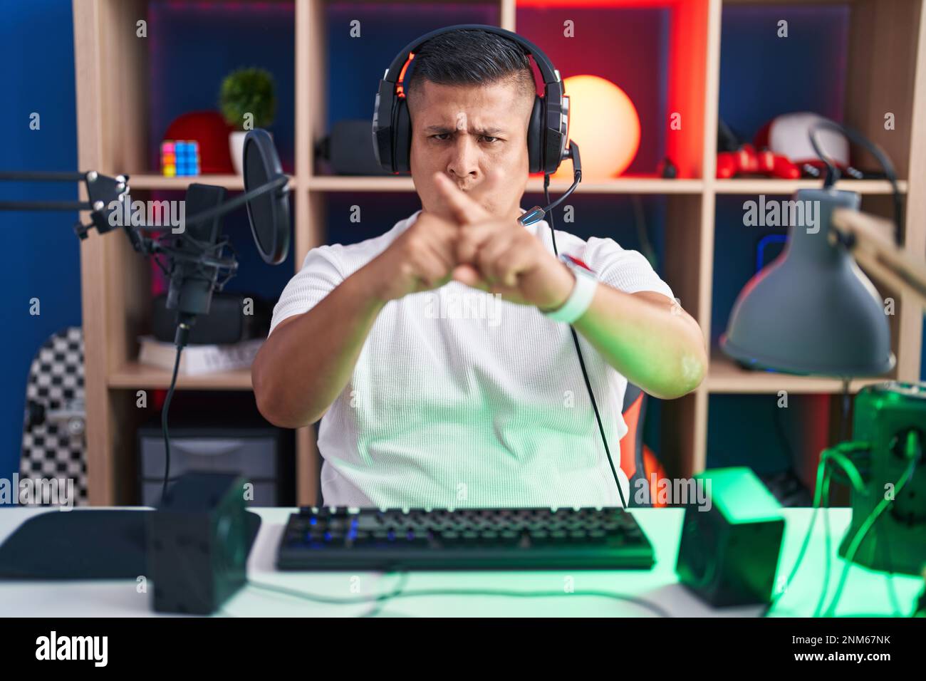 Young hispanic man playing video games rejection expression crossing ...