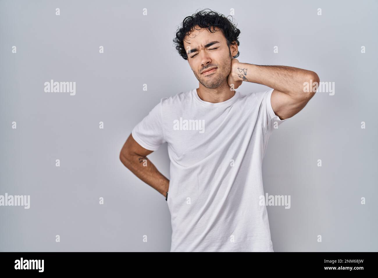 Hispanic man standing over isolated background suffering of neck ache ...