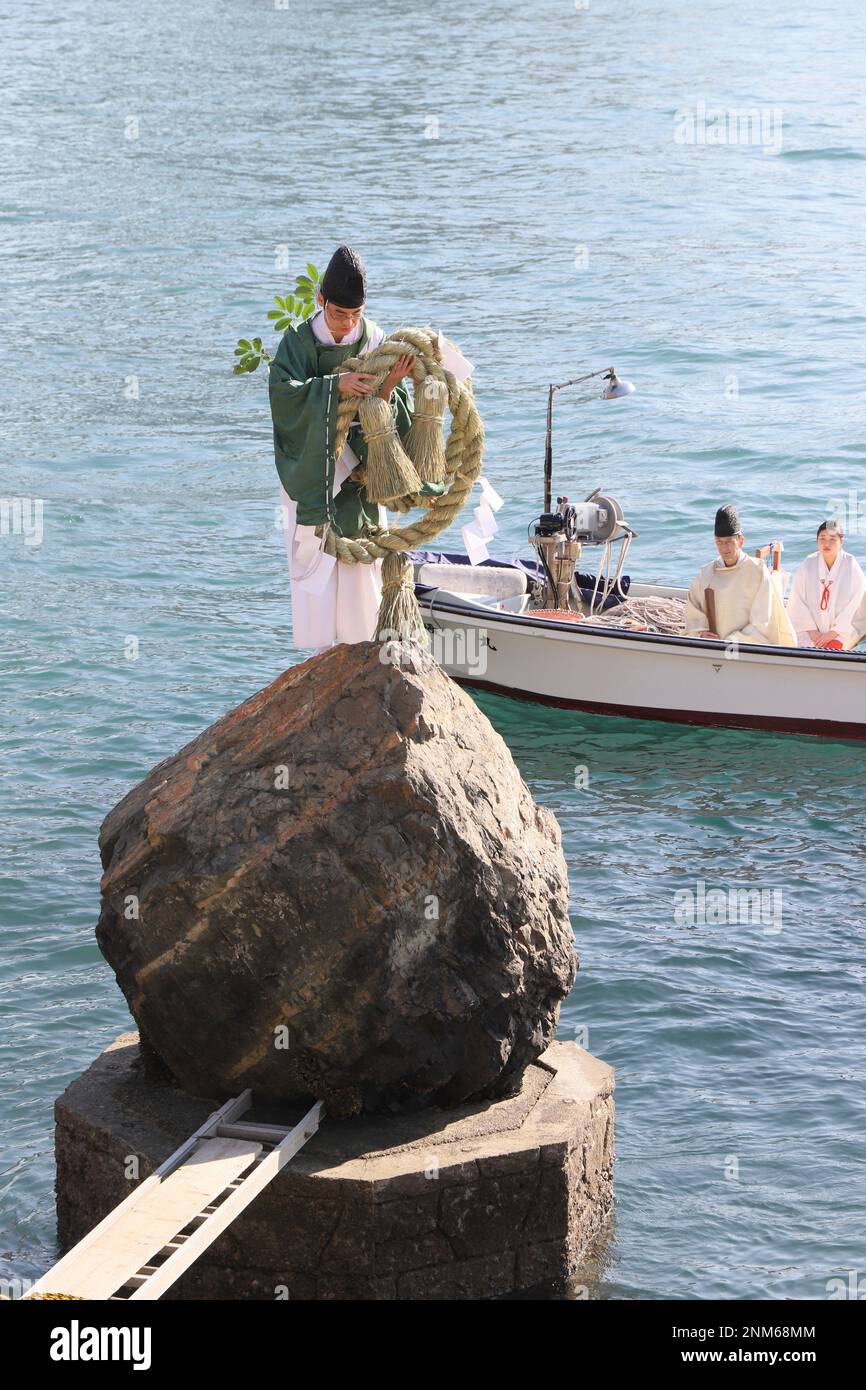 A Shinto priest, standing on a Eboshi rock, ties a sacred rope for ...