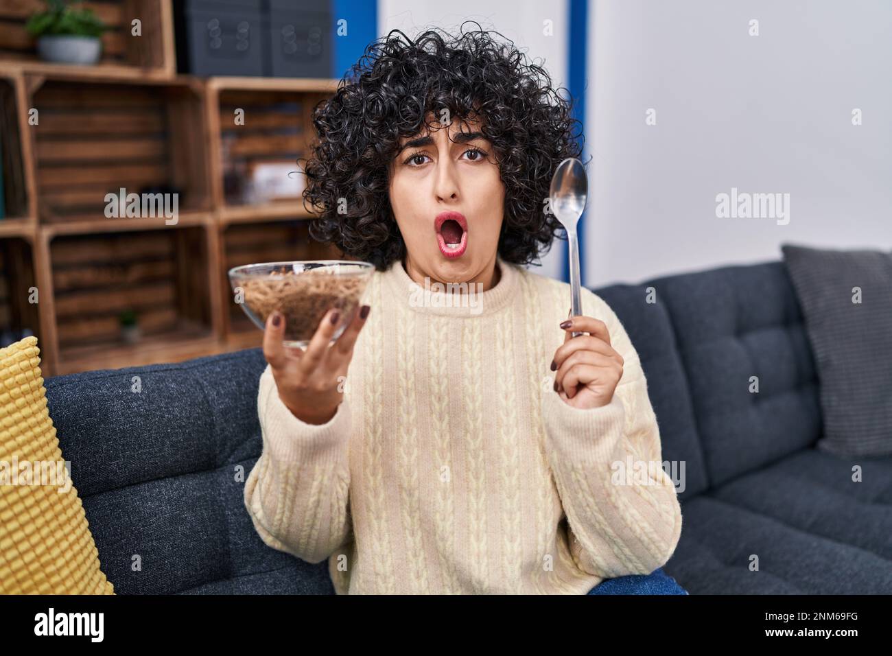 Young brunette woman with curly hair eating healthy whole grain cereals ...