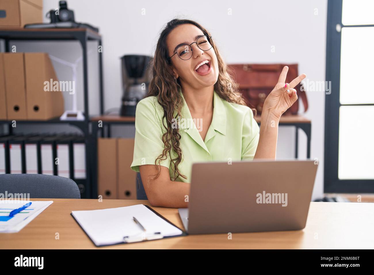 Young hispanic woman working at the office wearing glasses smiling with ...