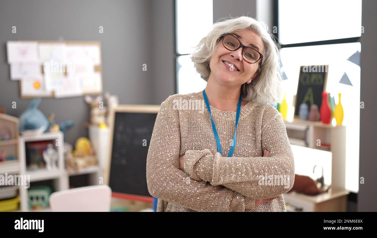 Middle age woman with grey hair preschool teacher smiling confident ...