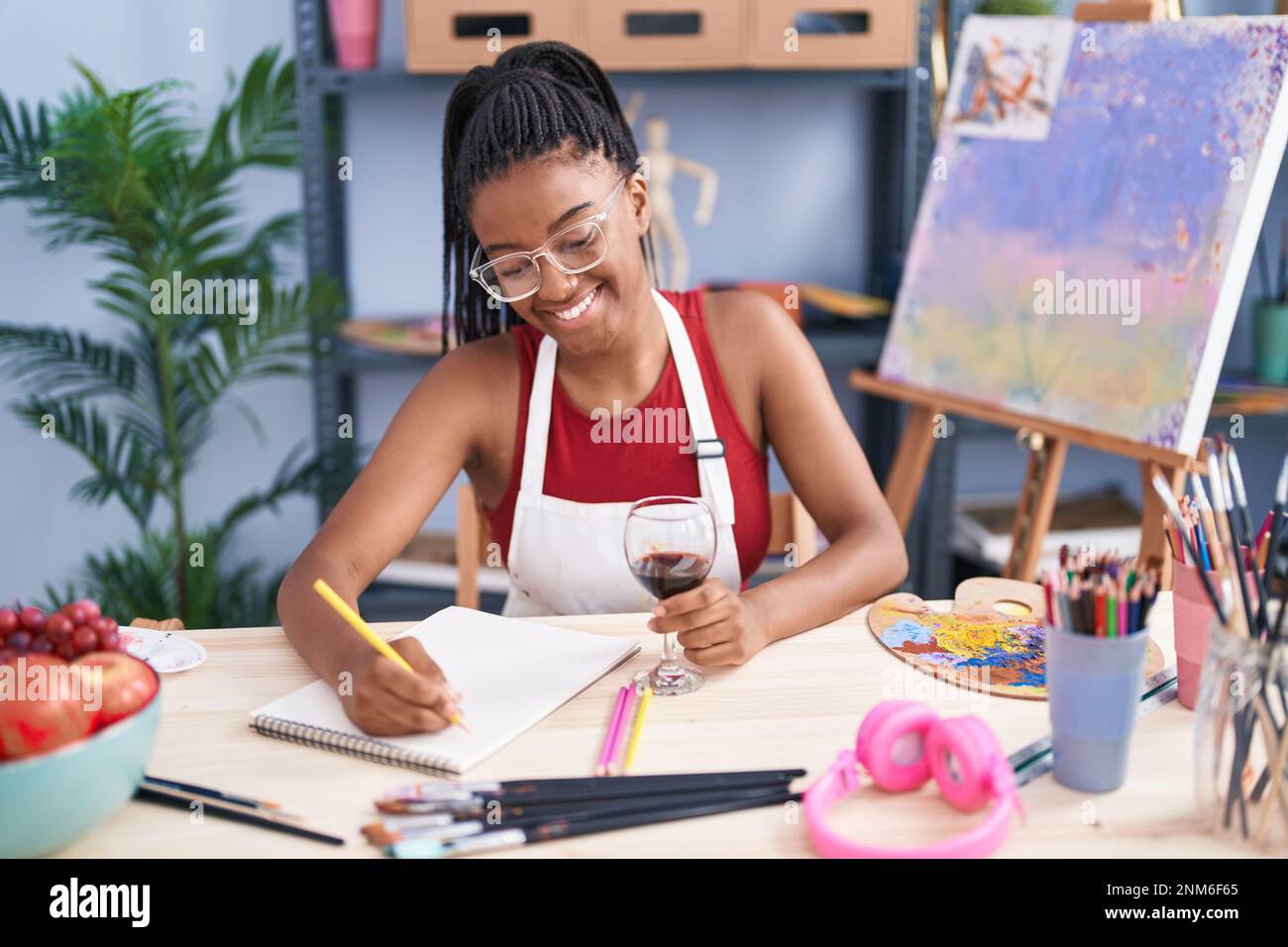 African american woman artist drinking wine drawing on notebook at art ...