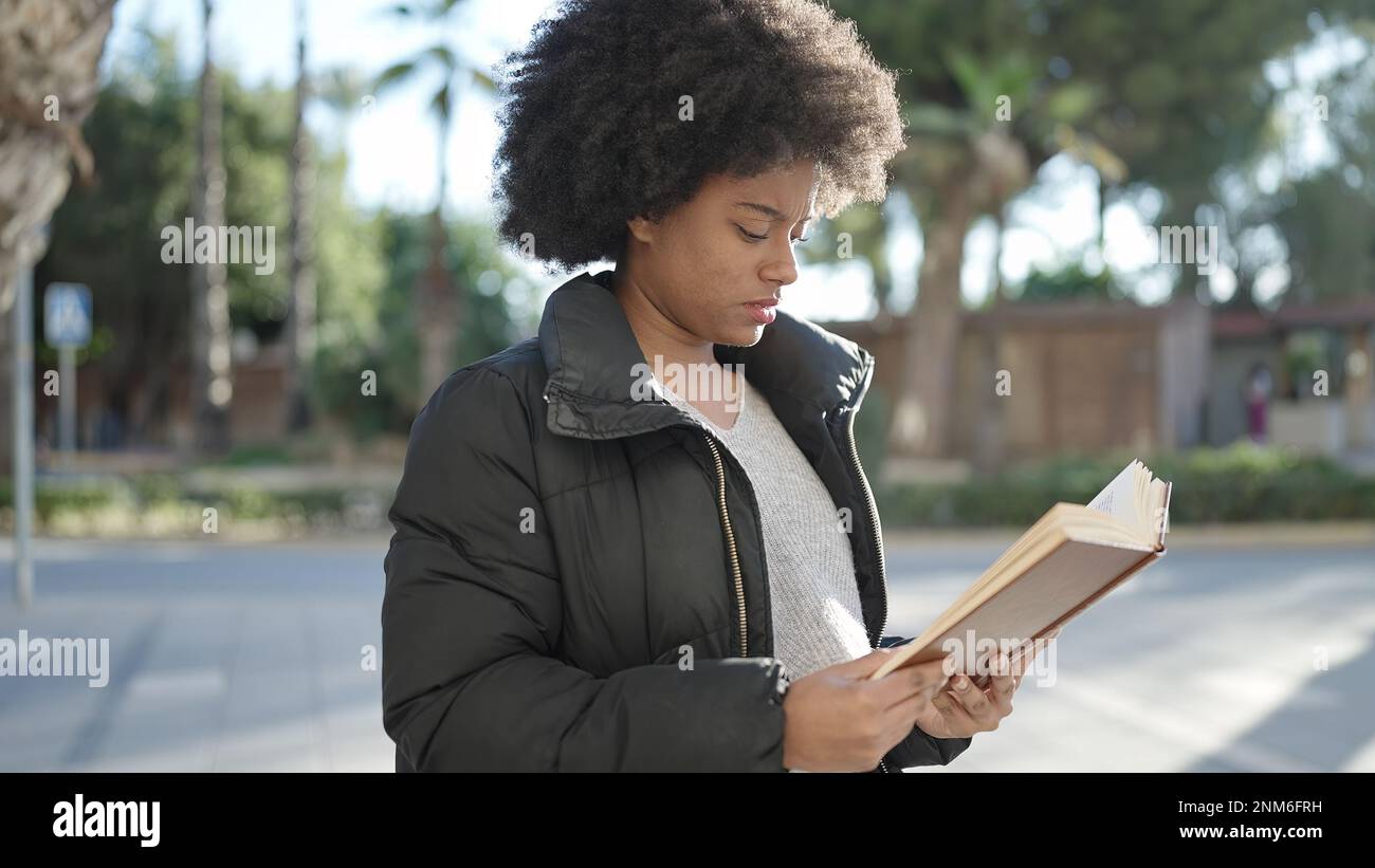 African american woman reading book at street Stock Photo - Alamy