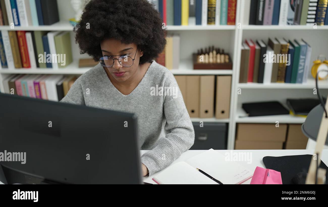 African american woman student using computer studying at library ...