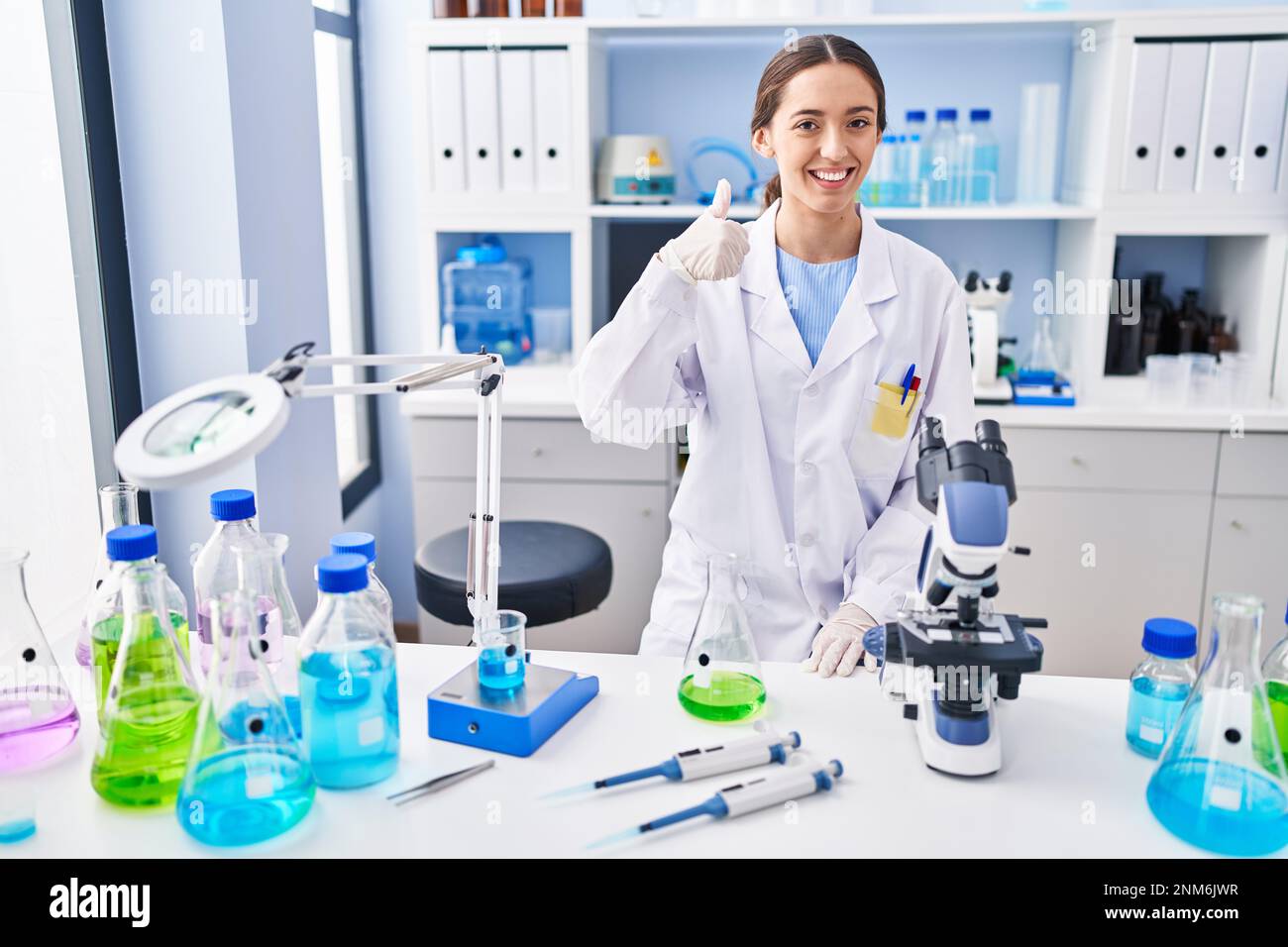 Young brunette woman working at scientist laboratory smiling happy and ...