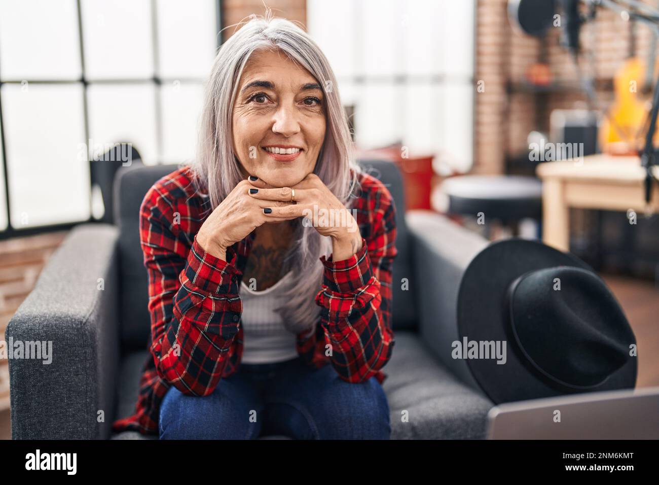 Middle age grey-haired woman artist smiling confident sitting on sofa ...
