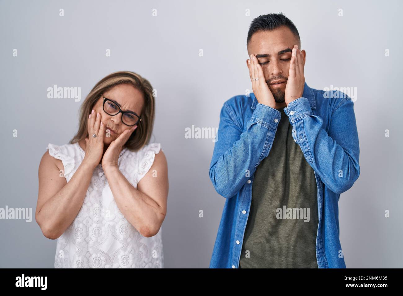 Hispanic mother and son standing together tired hands covering face ...