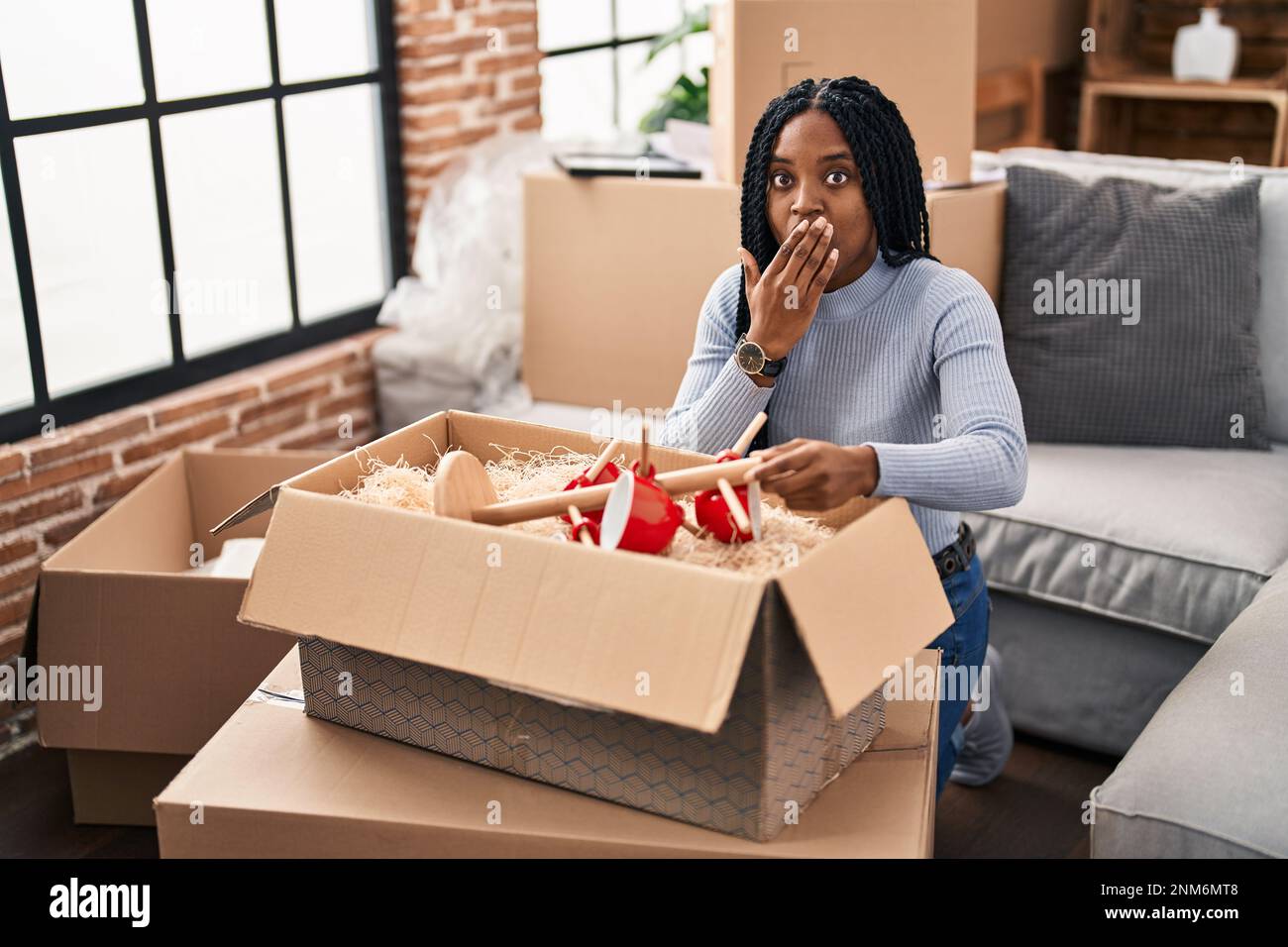 African american woman moving to a new home opening boxes covering ...