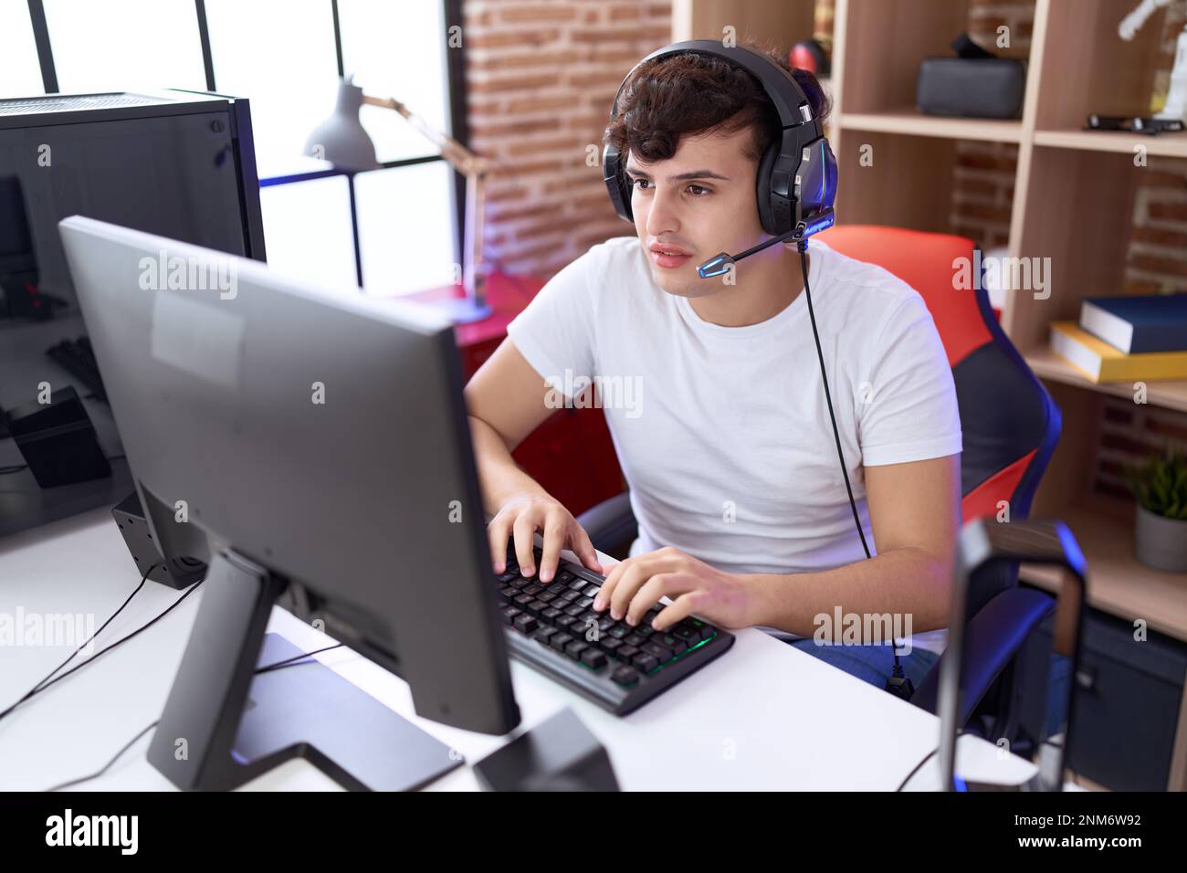 Non binary man streamer playing video game using computer at gaming ...