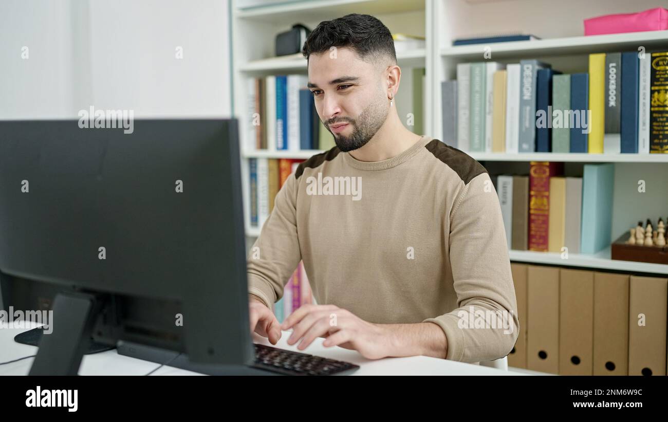 Young arab man student using computer studying at university classroom ...