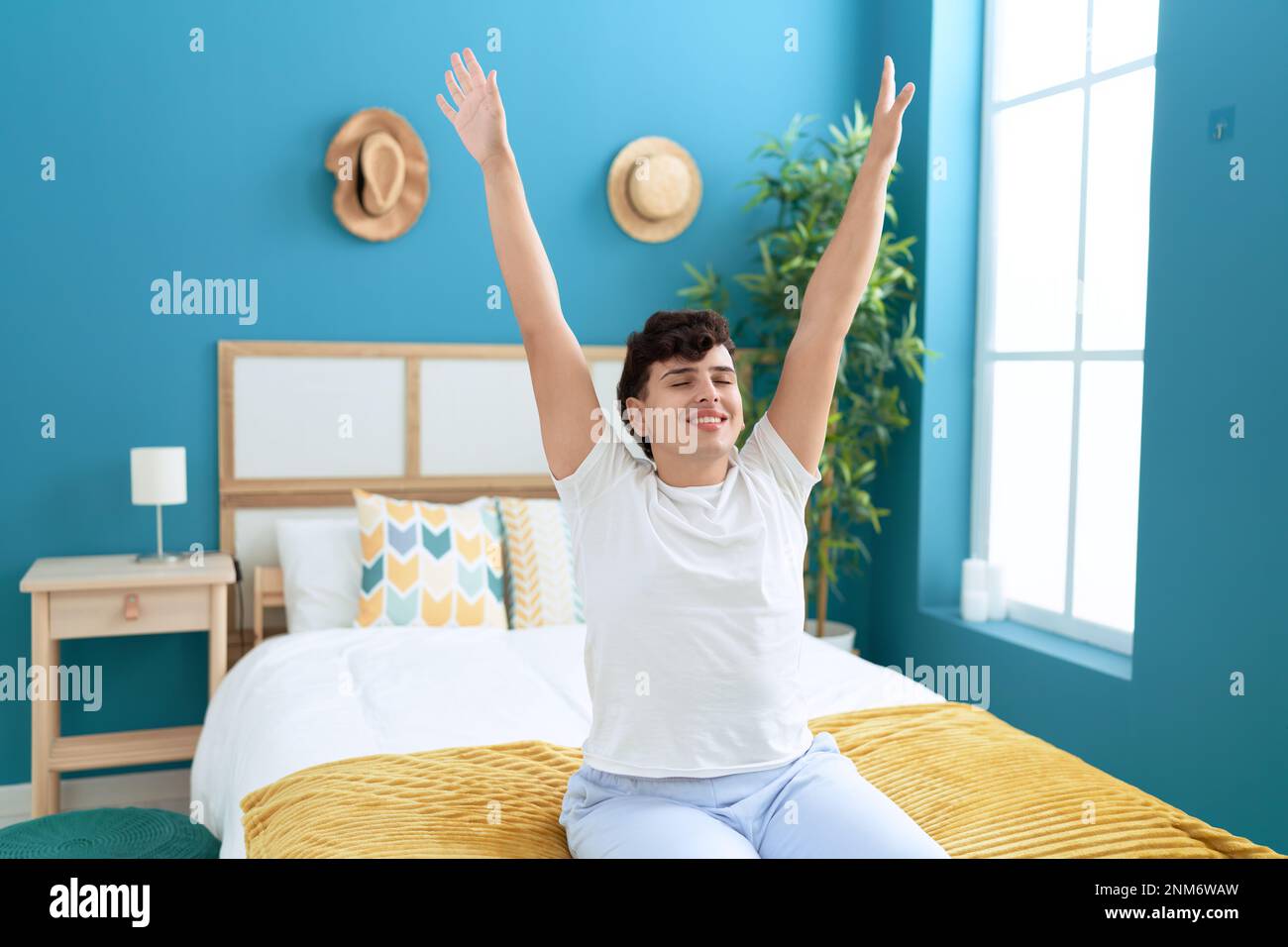 Non binary man waking up stretching arms at bedroom Stock Photo - Alamy