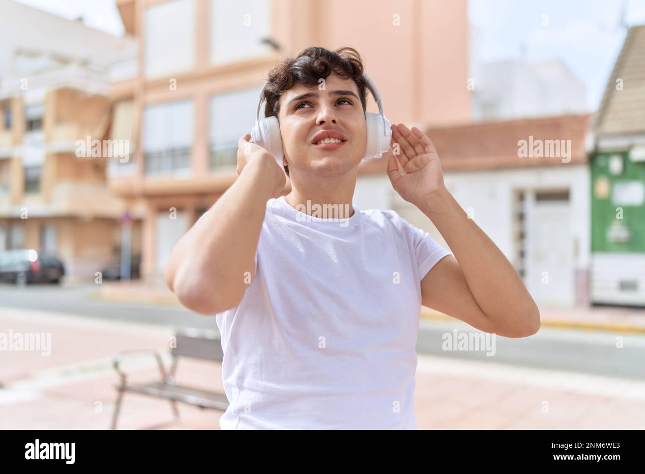 Non binary man listening to music standing at street Stock Photo - Alamy