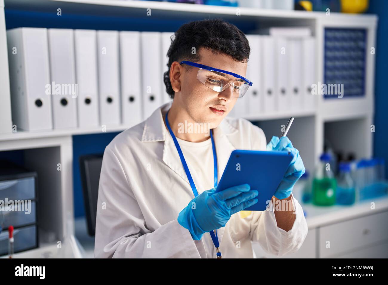 Young non binary man scientist write on touchpad at laboratory Stock Photo - Alamy