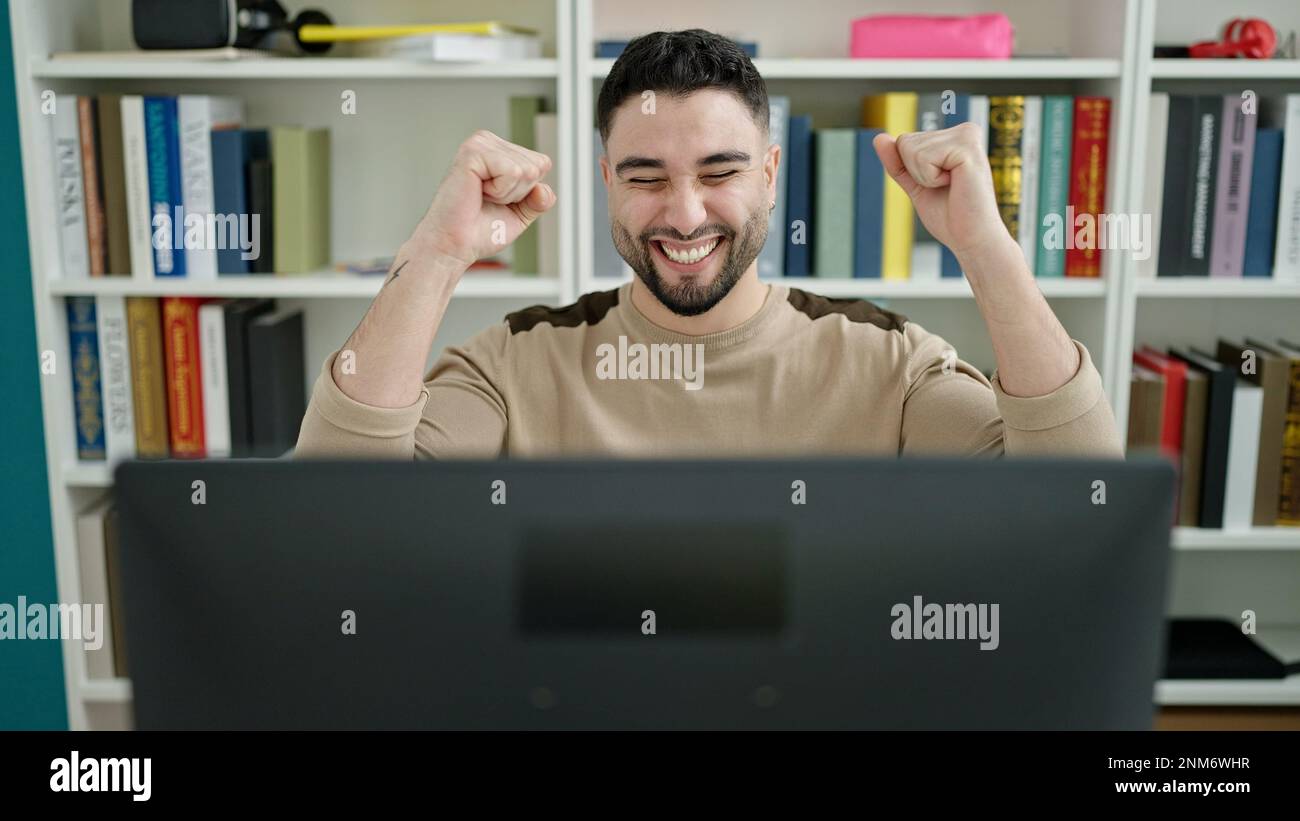Young arab man student using computer studying at university classroom ...