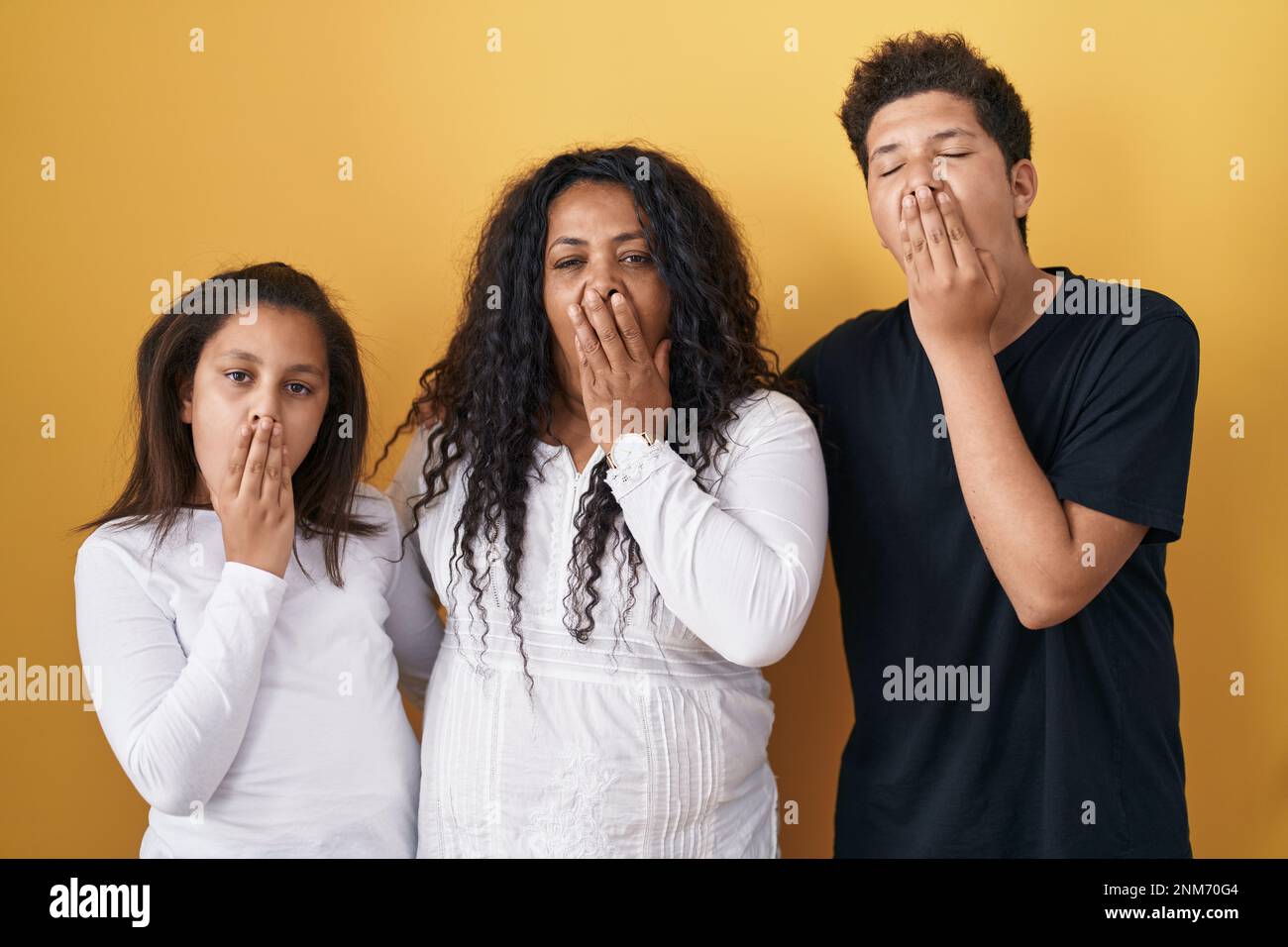Family of mother, daughter and son standing over yellow background ...