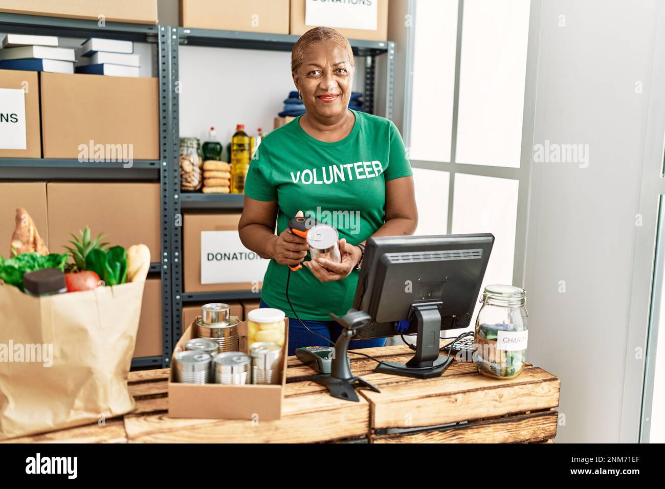 Senior african american woman wearing volunteer uniform scanning food ...