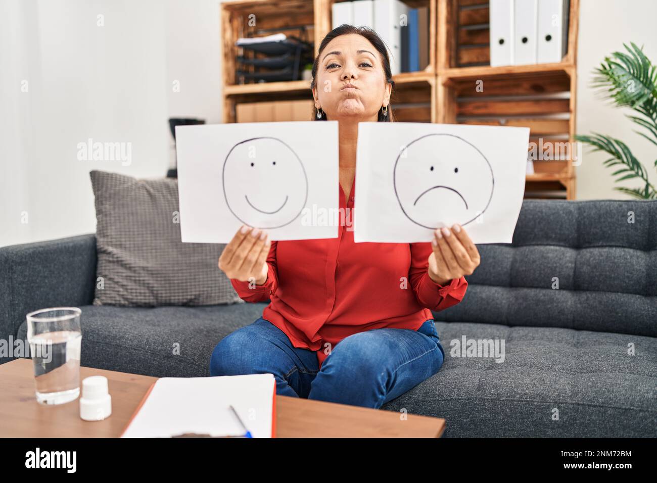 Middle age hispanic woman working on depression holding sad to happy ...