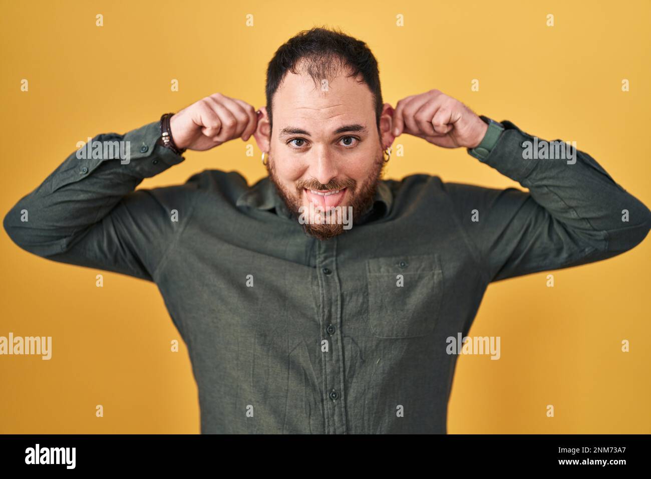 Plus size hispanic man with beard standing over yellow background ...