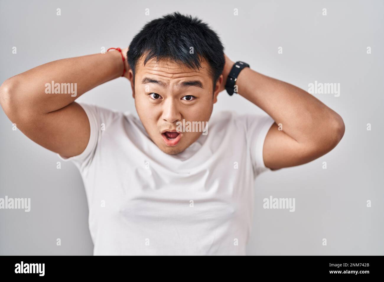 Young chinese man standing over white background crazy and scared with ...
