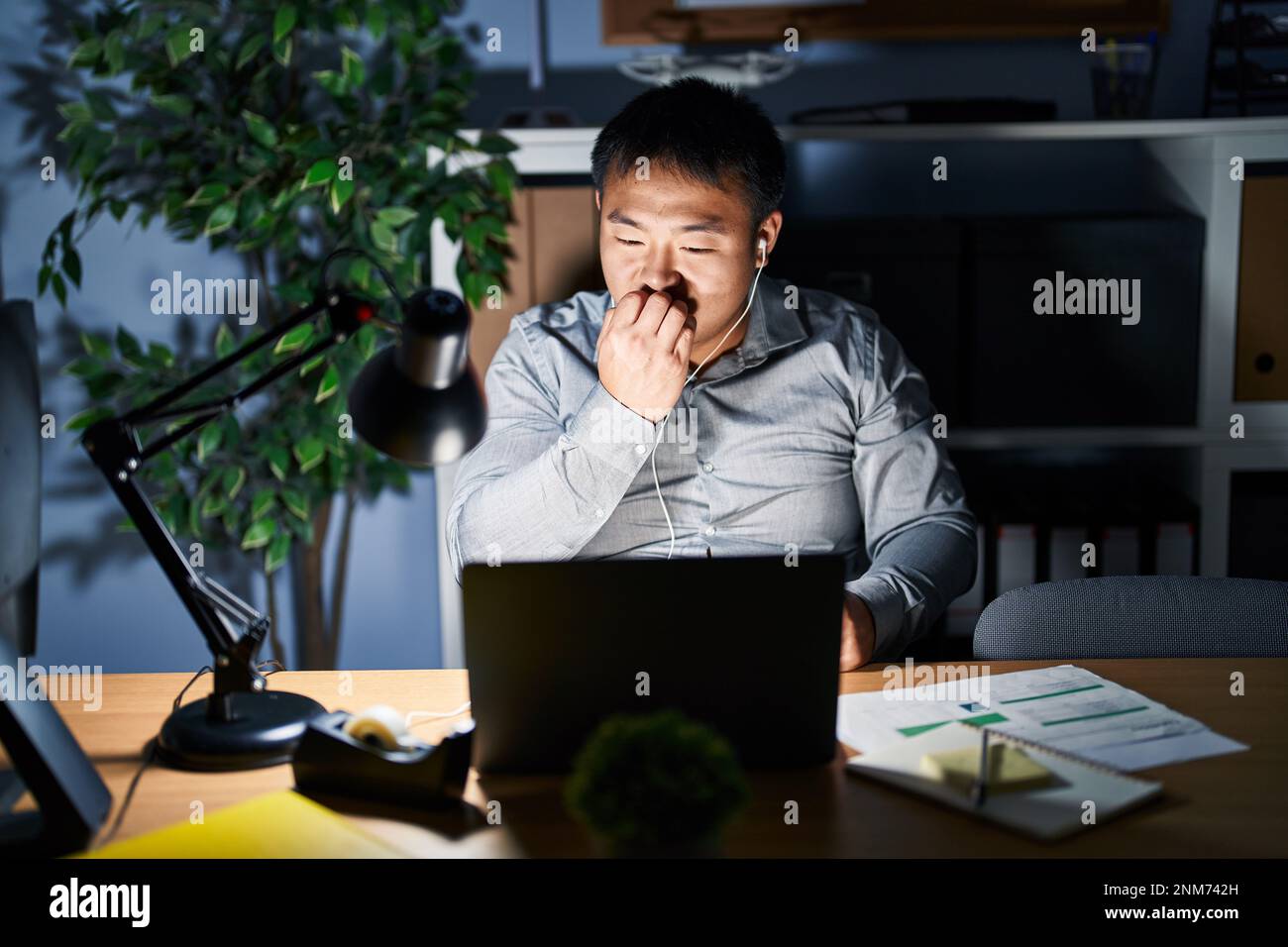 Young chinese man working using computer laptop at night looking ...