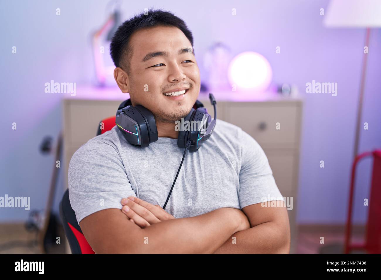 Young chinese man streamer smiling confident sitting with arms crossed ...