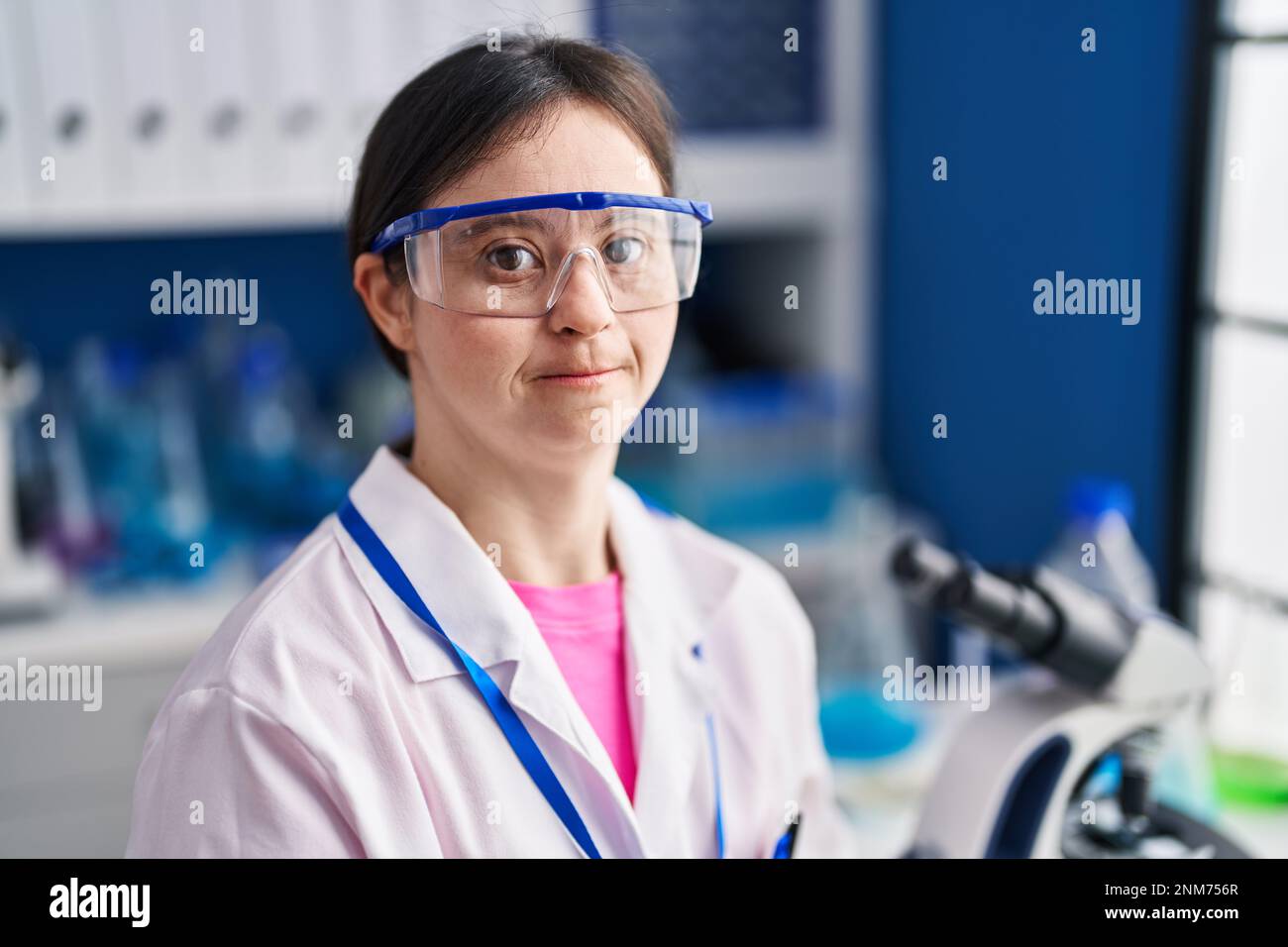 Young woman with down syndrome scientist smiling confident standing at laboratory Stock Photo ...