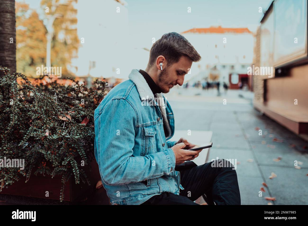 A gappy student sitting in a park using a smartphone and wireless ...