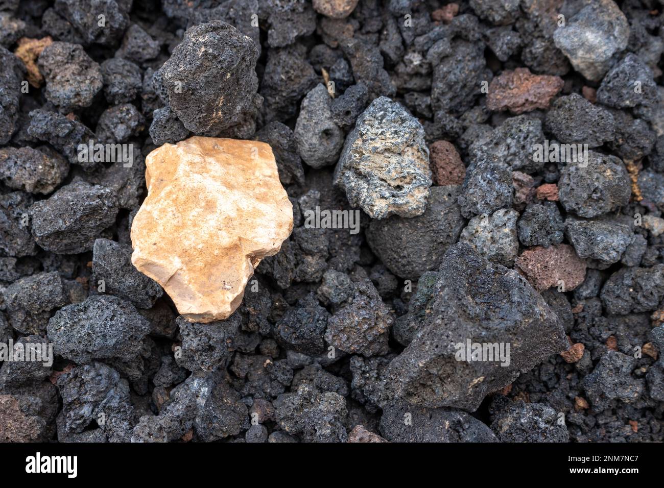 Structure of volcanic black and dark brown stones with one light brown ...
