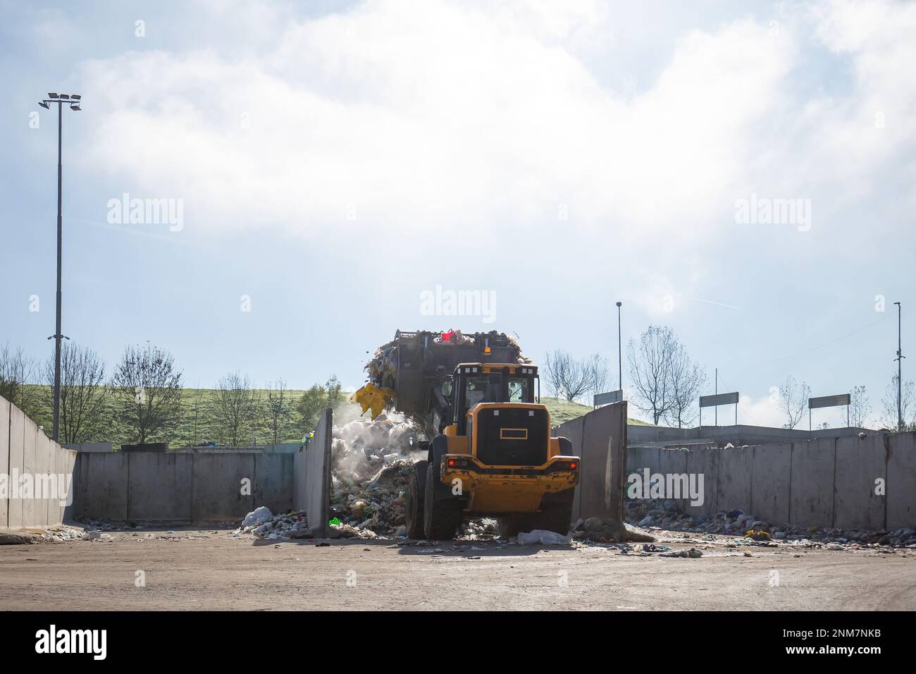 Yellow wheel loader, with lifted scrap grapple, moving along the ...