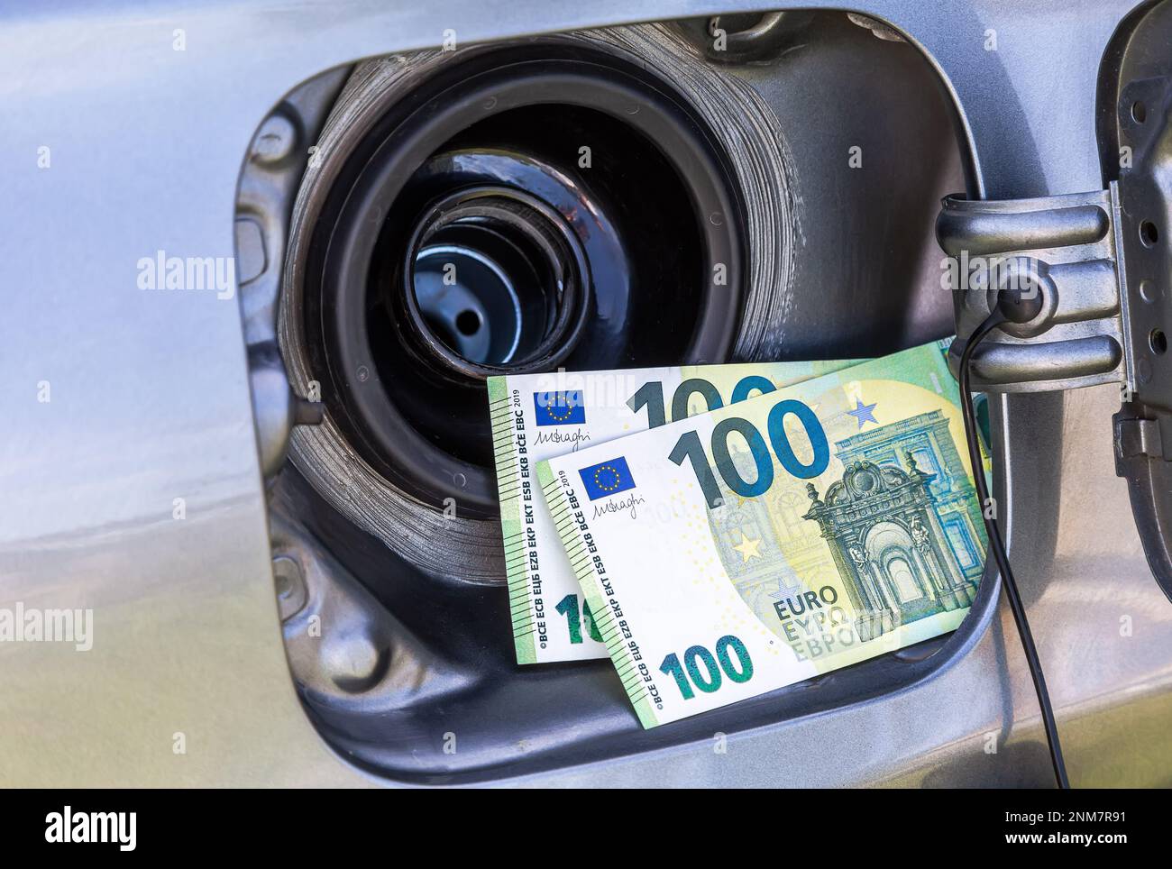 Two one hundred euro notes attached to an open fuel tank, symbol for ...