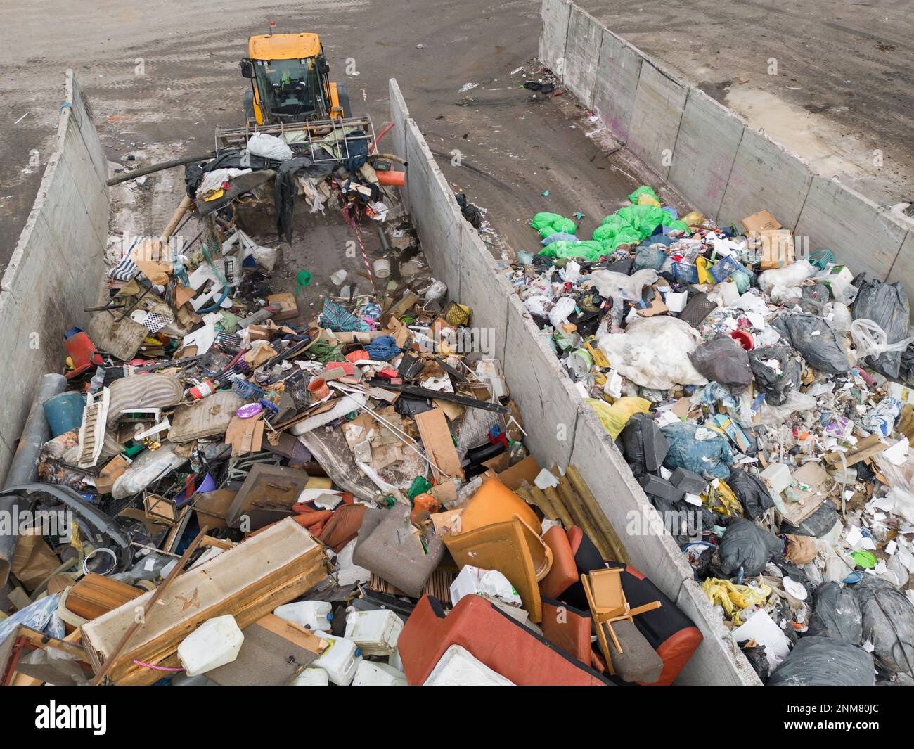 Yellow skid steer loader moving wooden waste material, shaking out a ...