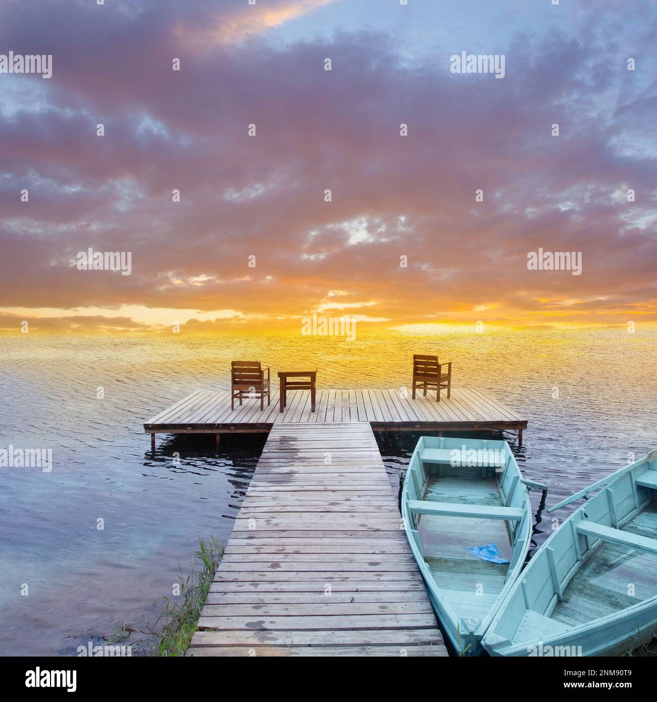 Boats, jetty, ocean and beautiful yellow and orange sunset Stock Photo ...
