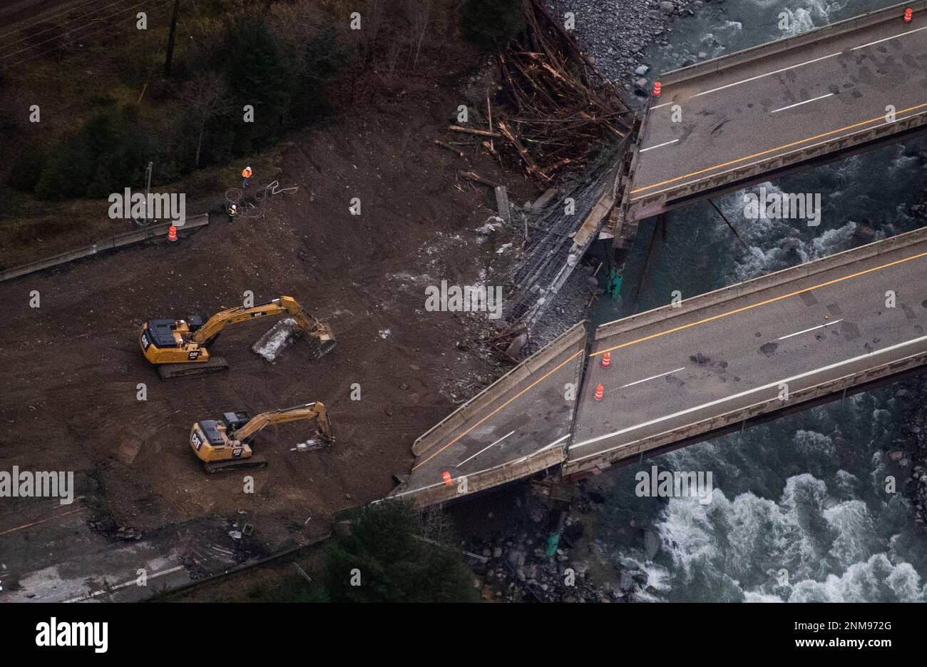 Workers view collapsed sections of bridges destroyed by severe flooding ...