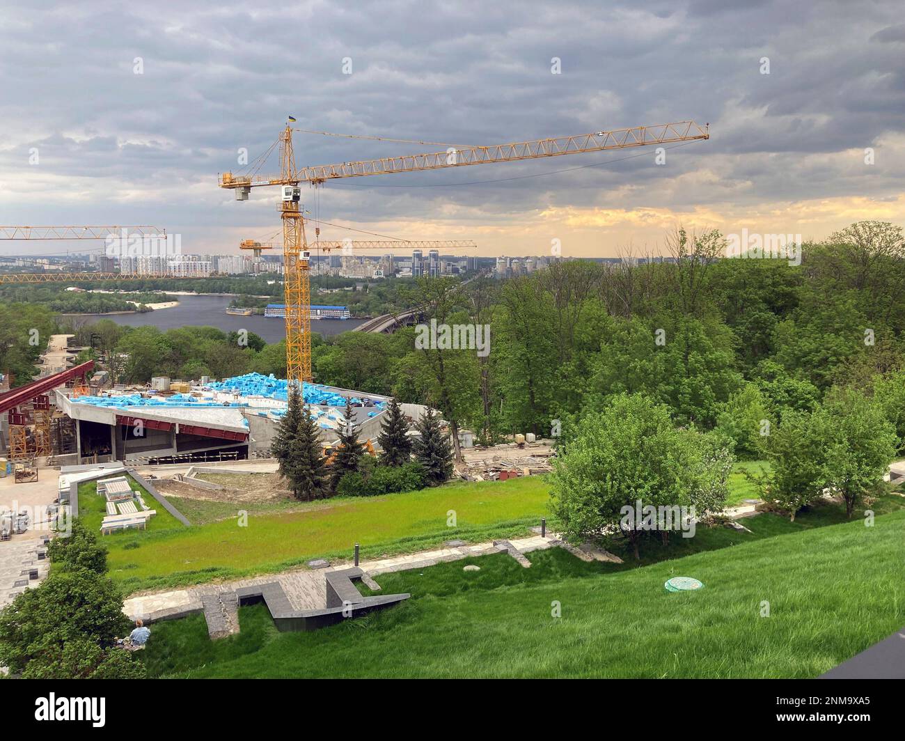 Construction site, three tall tower cranes and blue building materials ...