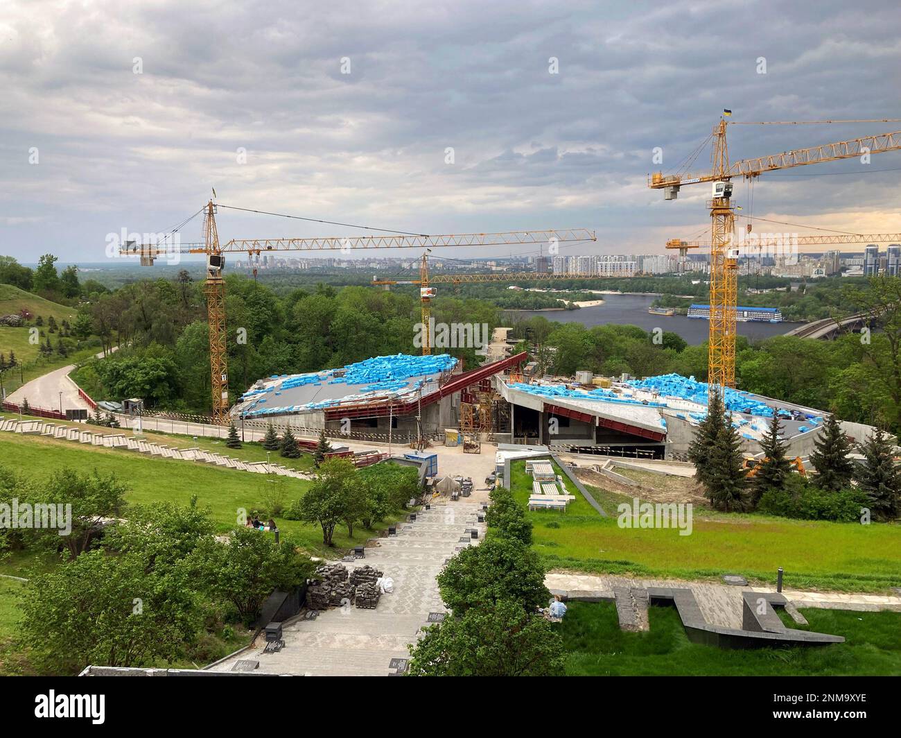 Construction site, three tall tower cranes and blue building materials ...
