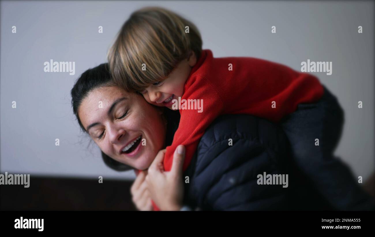 Candid mother and child embrace at home. Little boy hugging mom back ...