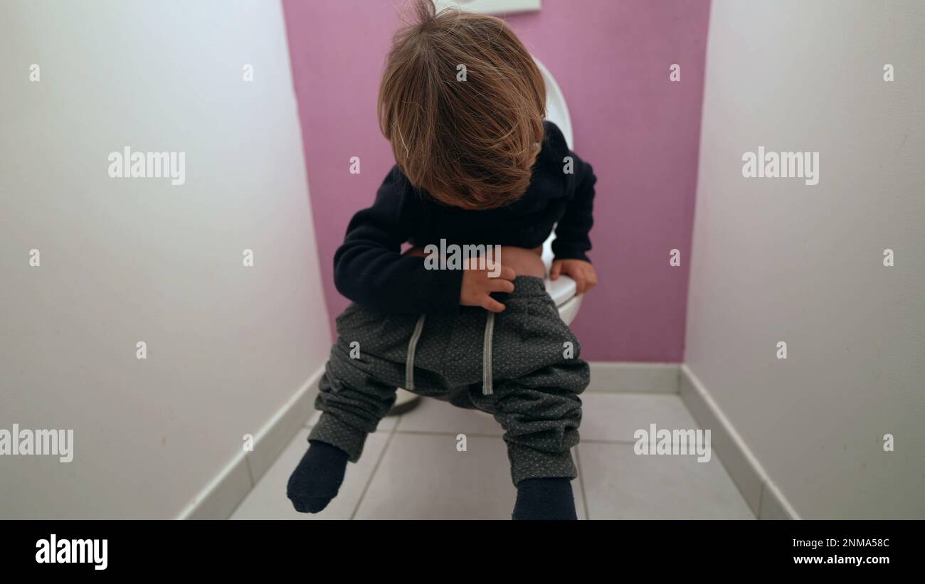 Child seated in toilet inside bathroom lavatory. One little boy Stock ...
