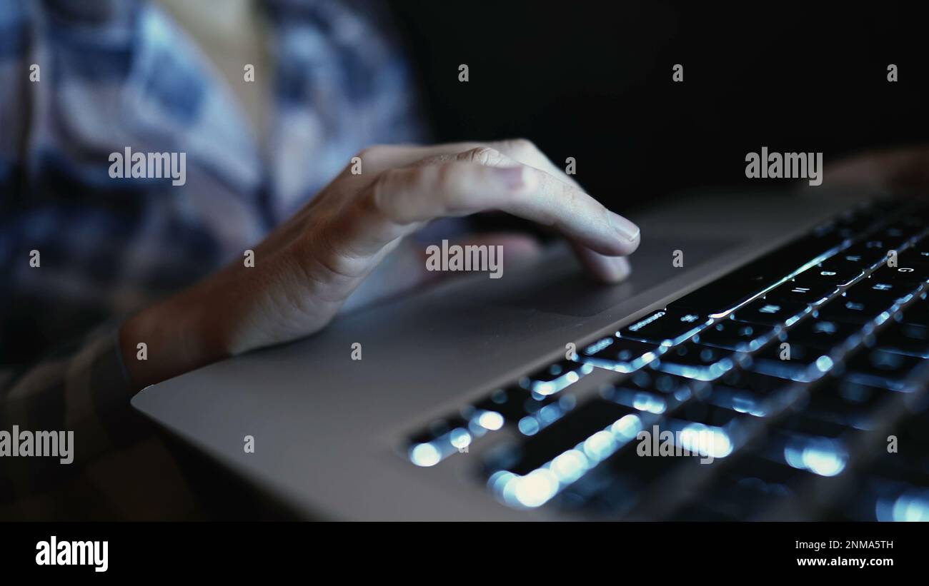 Closeup female hand using trackpag laptop at night. Person browses ...