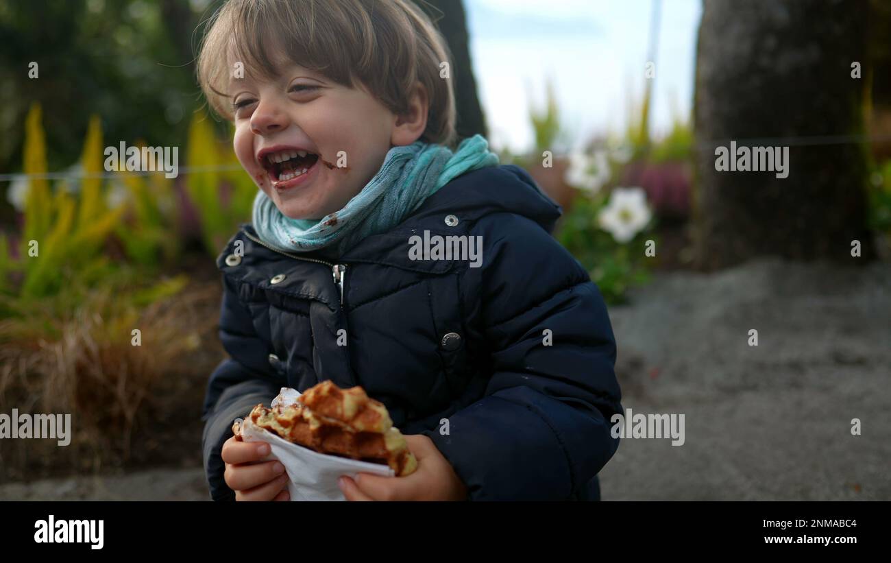 Happy child smiling at laughing while eating street food dessert ...