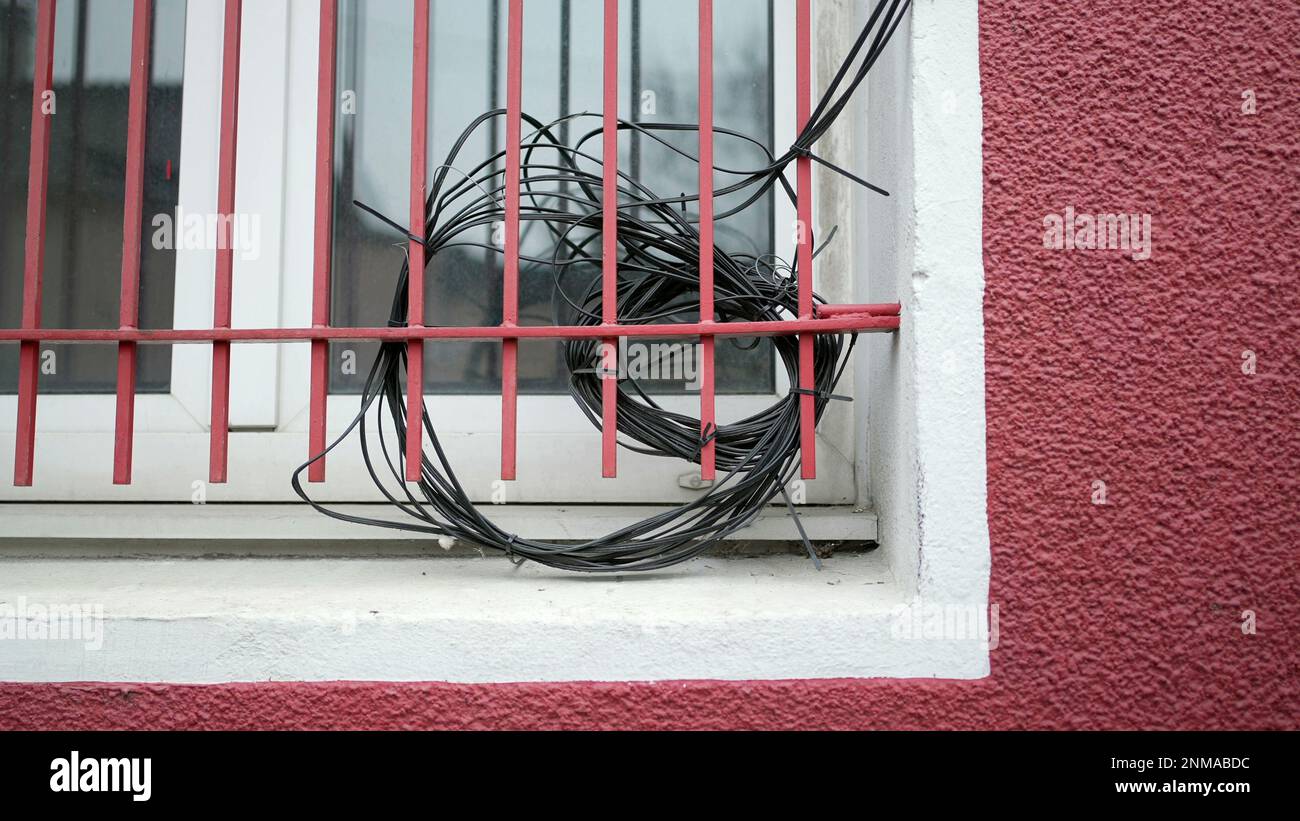 Electric wires mess on residential window with metal bars. Visual city ...