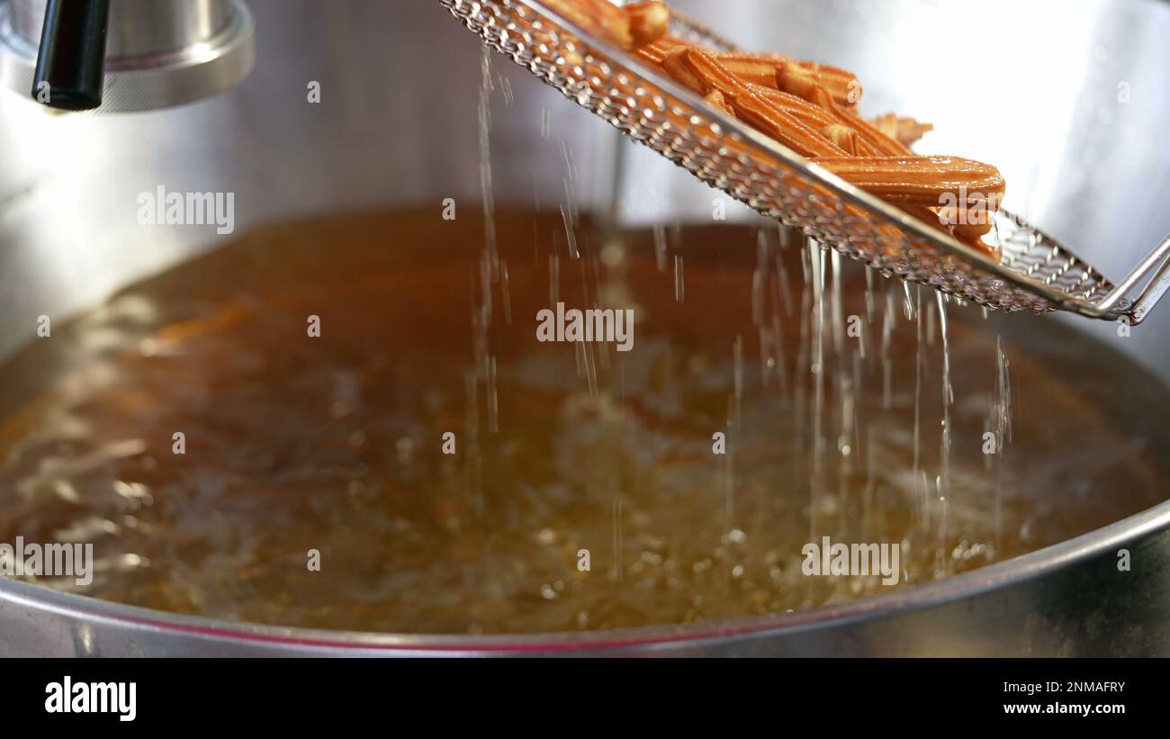 Preparing fried churros. Street food vendor prepares churros inside ...