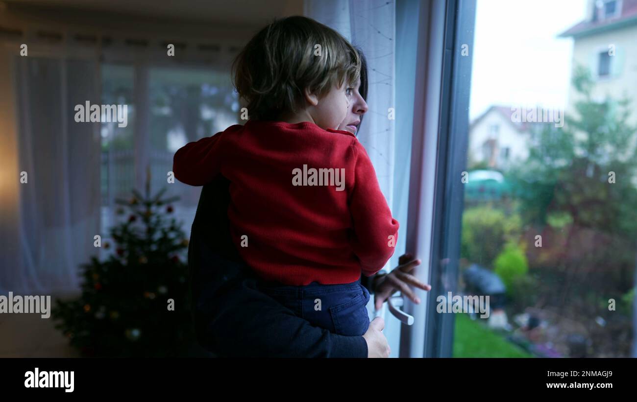 Mother holding toddler in arms and locking apartment window. Woman ...