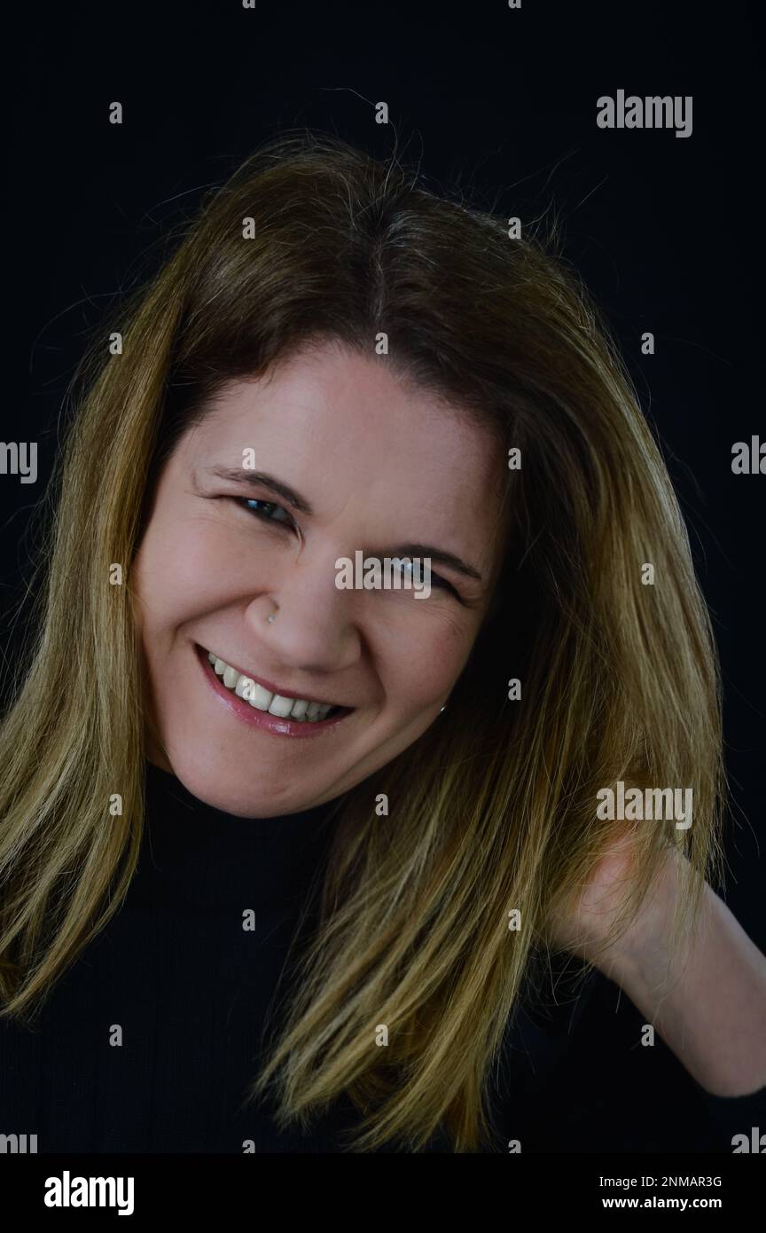 portrait of a beautiful blonde woman happily laughing while adjusting ...