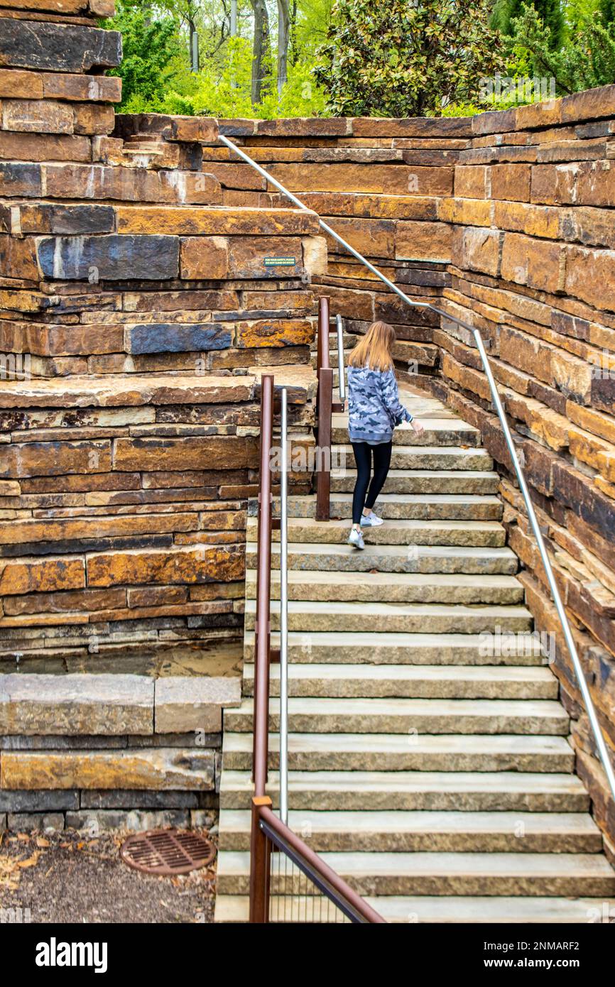 Girl with long red hair and camo jacket climbs rock steps in tall ...