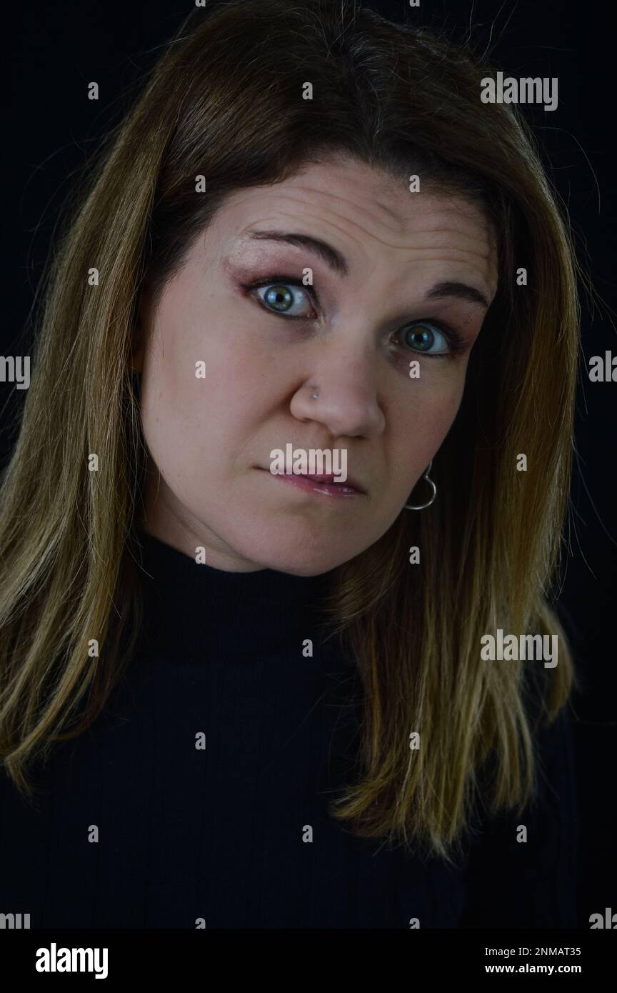 portrait of a beautiful blonde woman who widens her eyes and looks ...