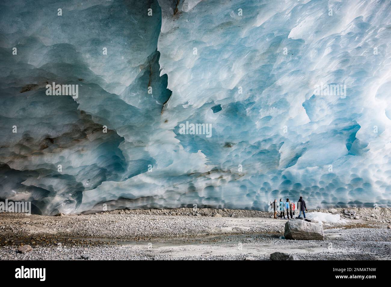 Hikers visit an ice cave formed at the end section of the Zinal glacier ...